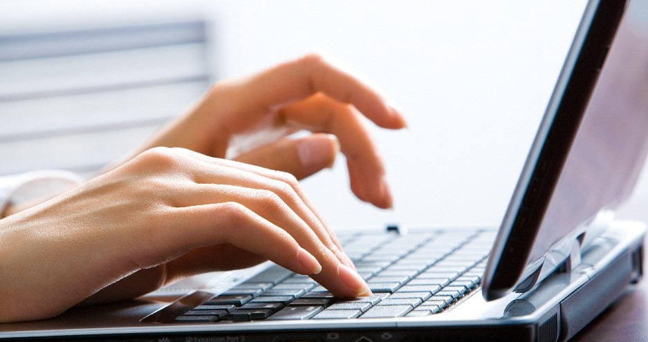 Image of female hands on the keys typing documents | CompareCamp.com